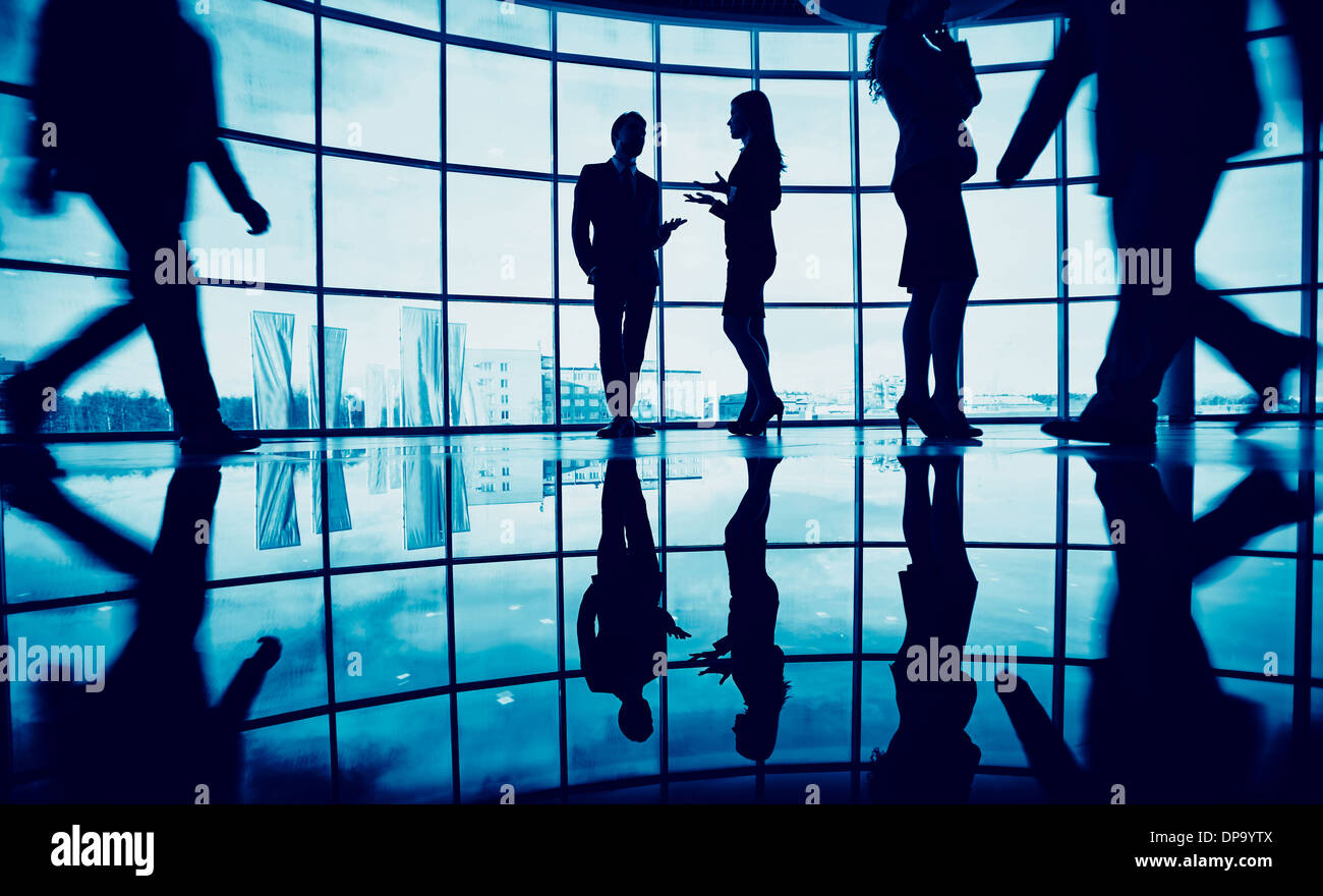 Several white collar workers communicating in office against window ...