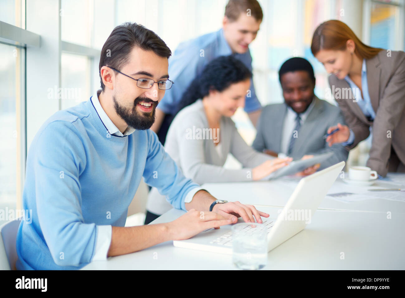 Group of business partners discussing ideas with their leader typing on ...