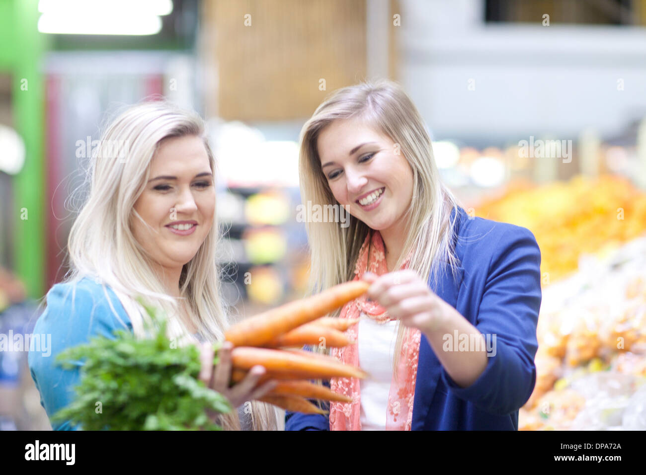 Two young women checking vegetables in indoor market Stock Photo - Alamy