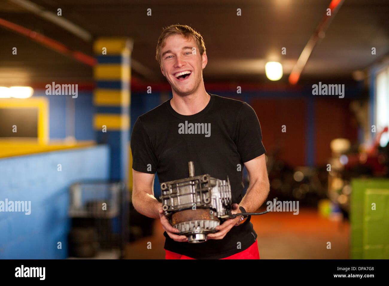 Mechanic holding engine in go cart workshop Stock Photo - Alamy