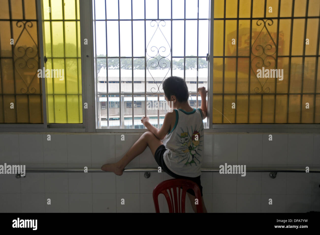 A boy born with protruding eyes and deformed limbs looks out the window ...