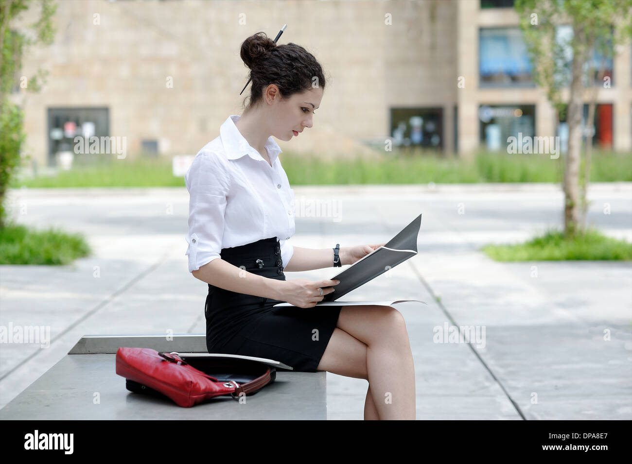 Office worker reading paperwork on bench Stock Photo - Alamy