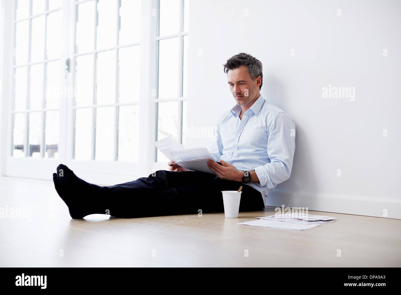 Man sitting on floor looking at paperwork Stock Photo - Alamy