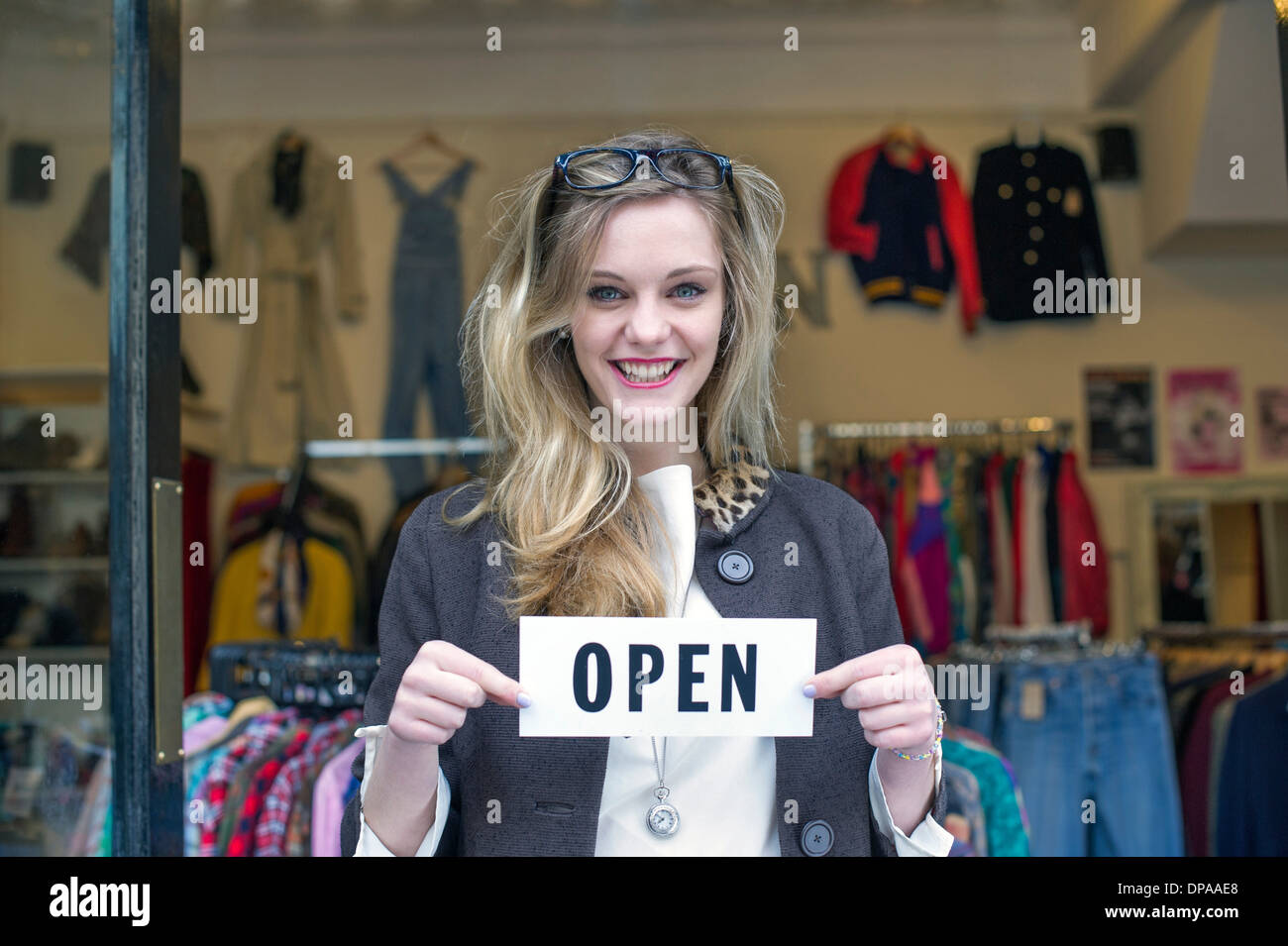 Woman holding open sign in clothes shop Stock Photo - Alamy