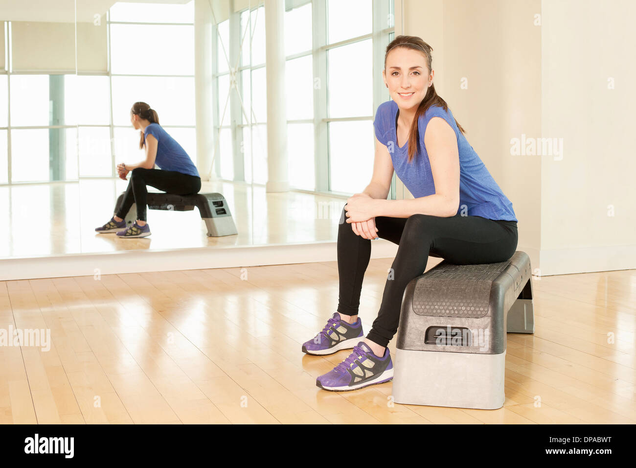 Woman sitting on step in gym Stock Photo - Alamy