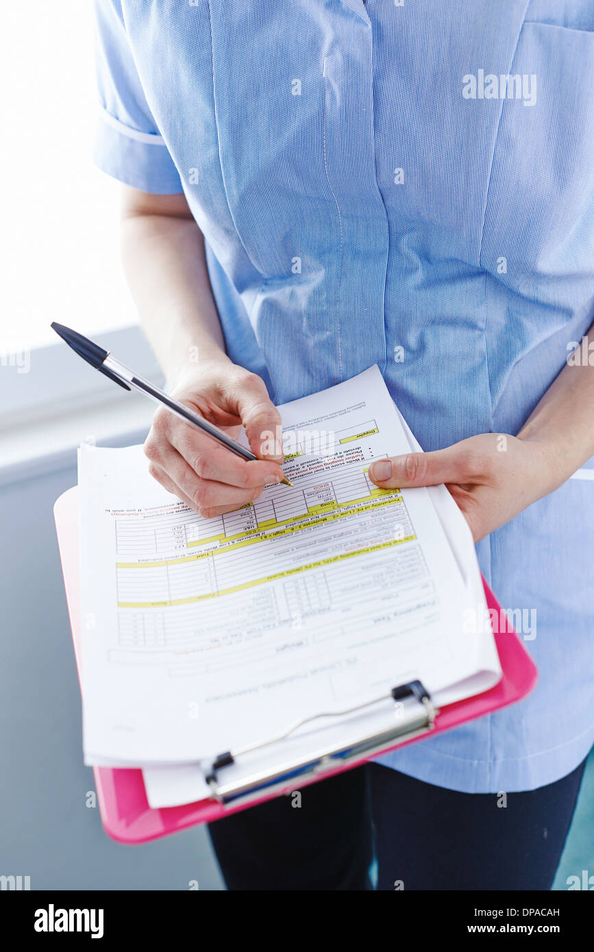 Mid-section of nurse writing paperwork Stock Photo - Alamy