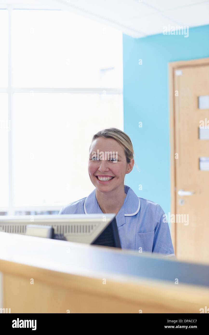 Nurse sitting at reception desk Stock Photo - Alamy