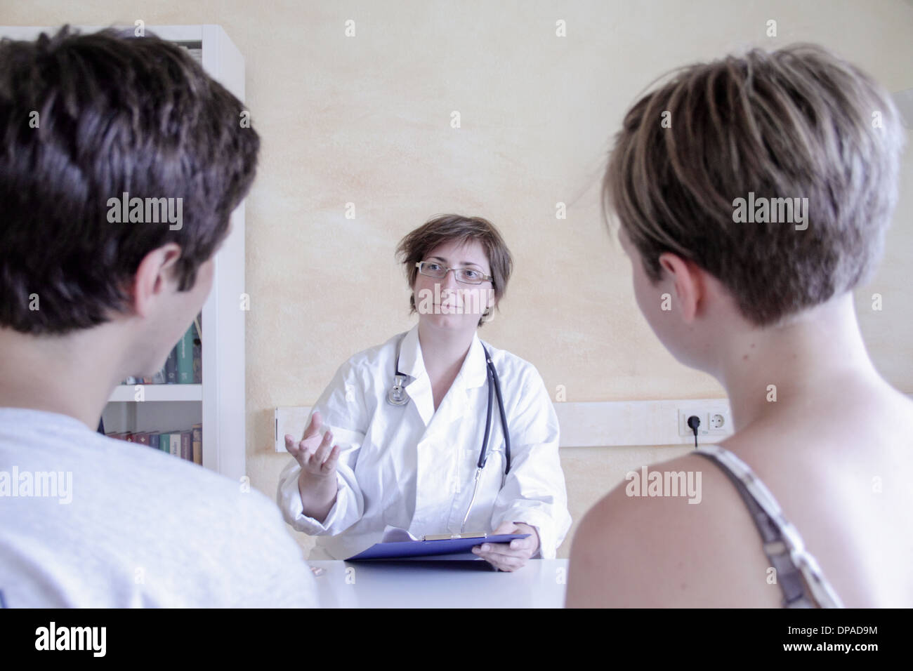 Doctor talking to young couple Stock Photo - Alamy