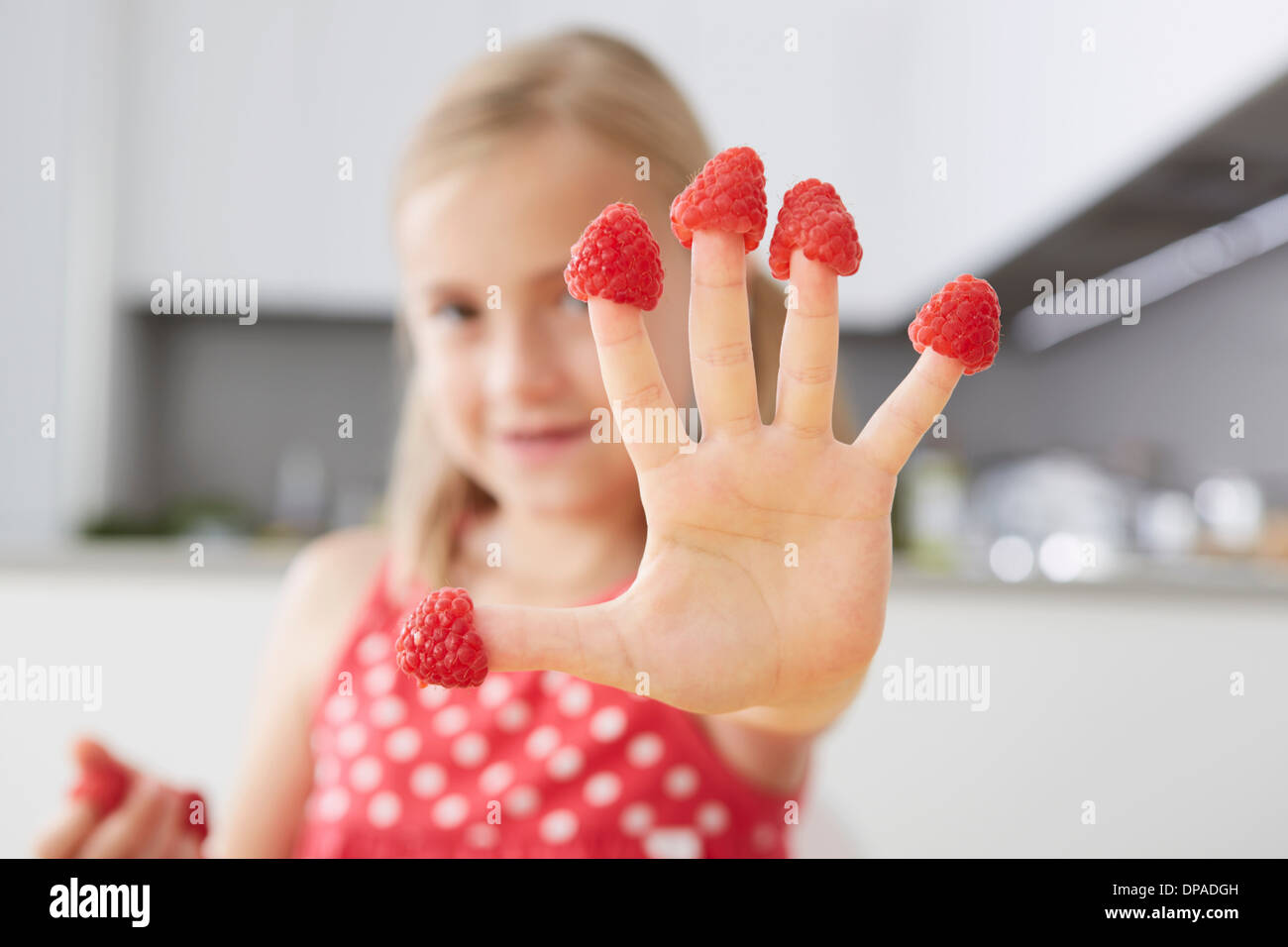 Girl putting raspberries on fingers Stock Photo - Alamy