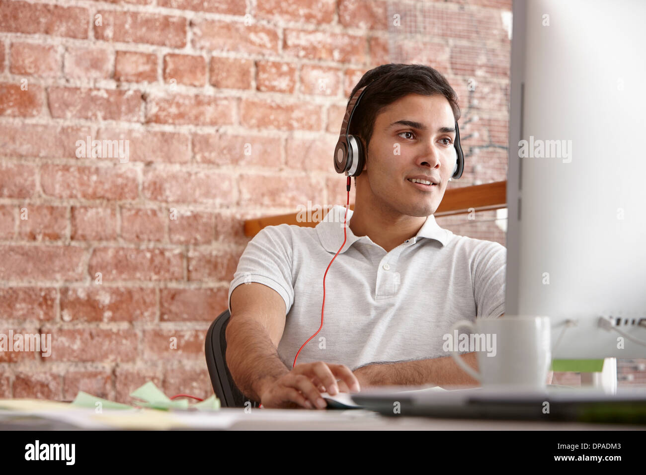 Young man using computer wearing headphones Stock Photo - Alamy