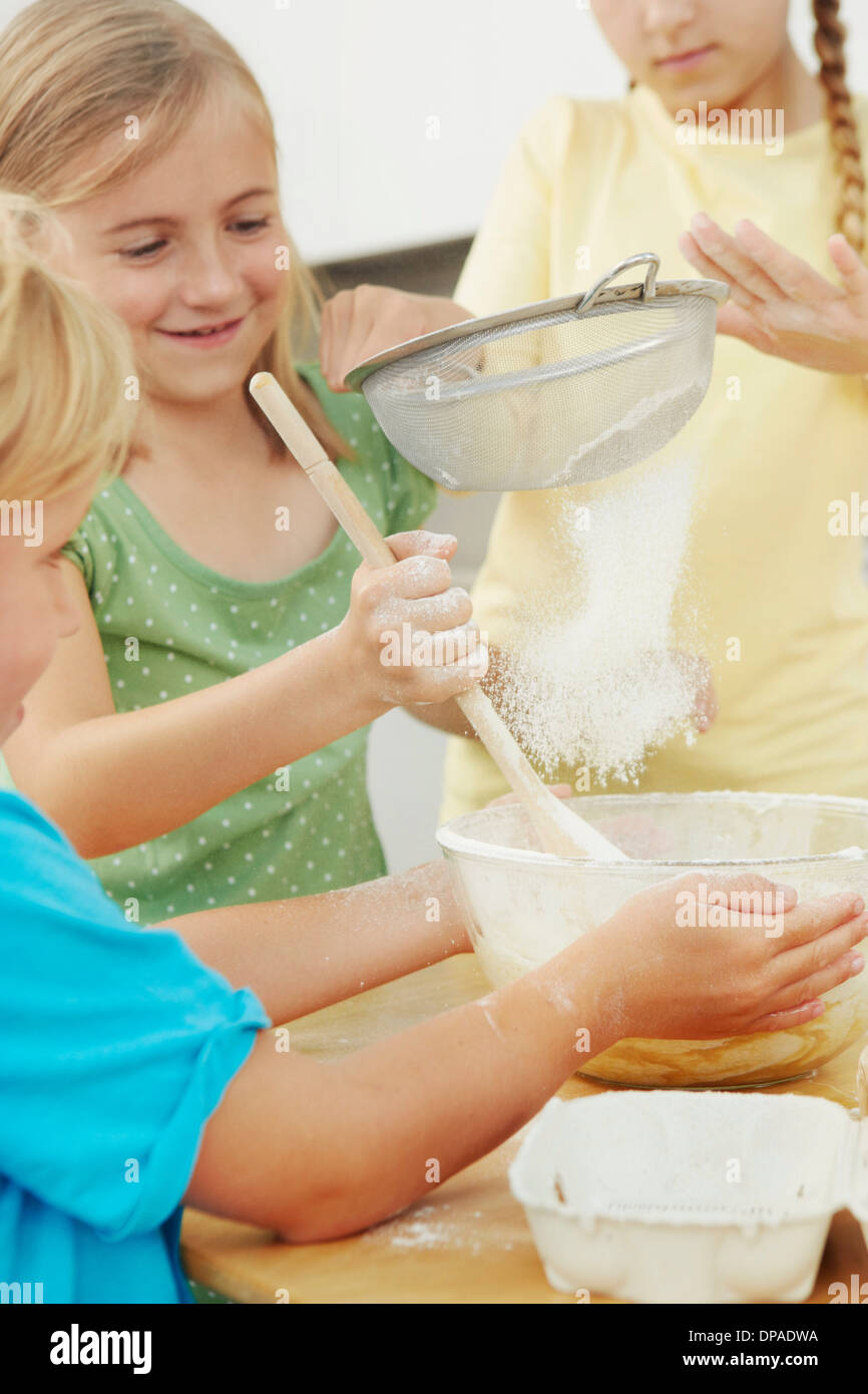 Children baking, sieving flour into mixing bowl Stock Photo - Alamy