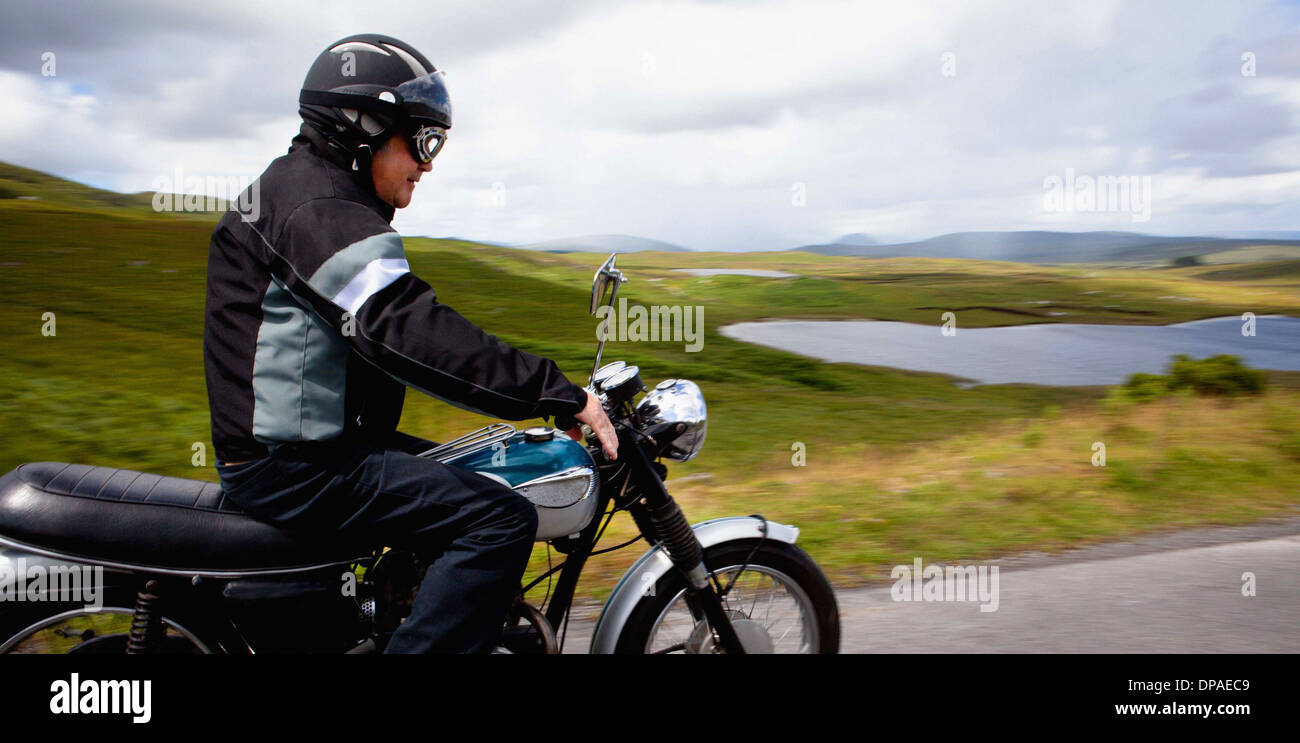 Senior male riding motorbike through rural landscape Stock Photo - Alamy