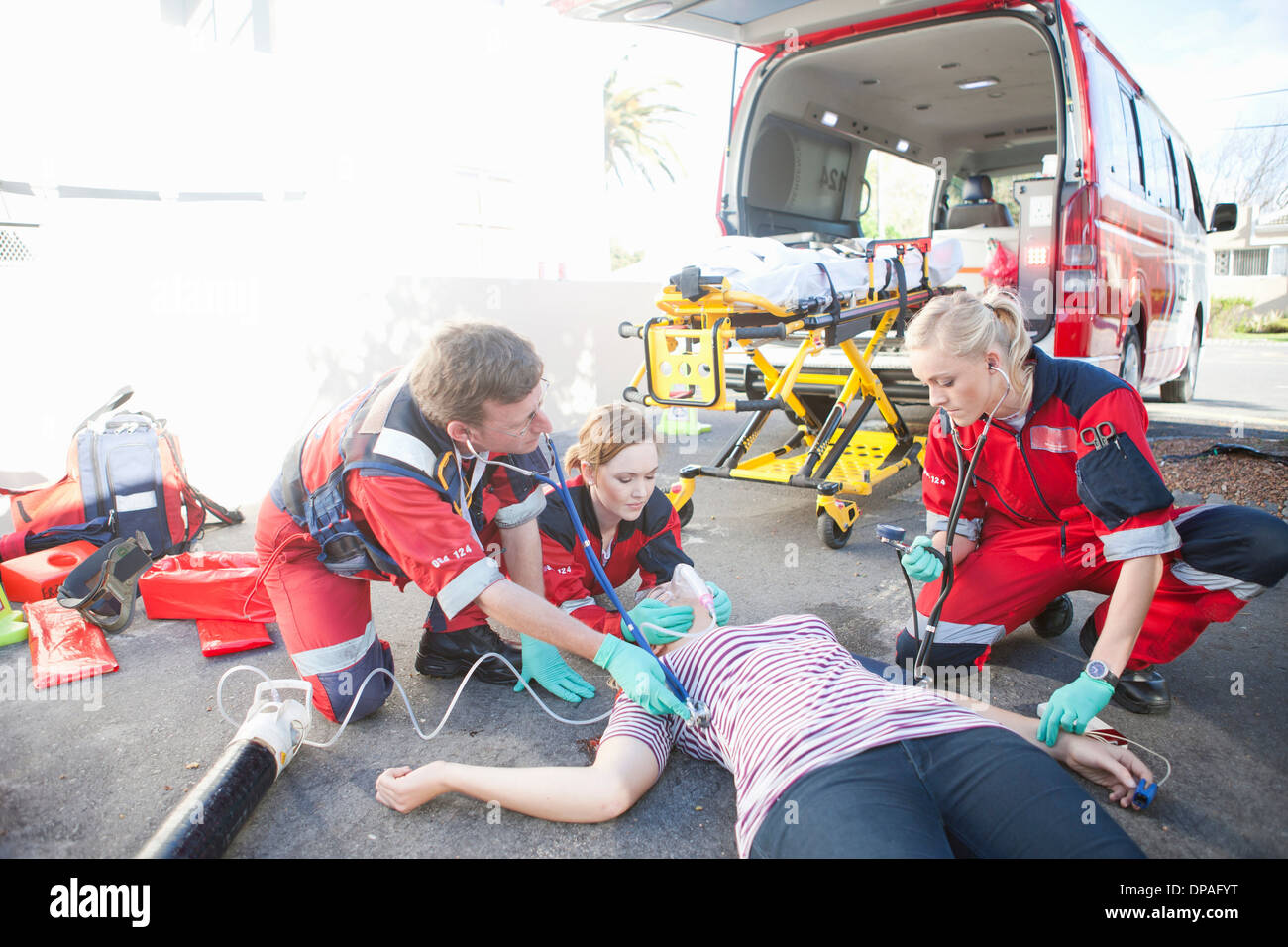 Paramedics tending patient lying on road Stock Photo - Alamy