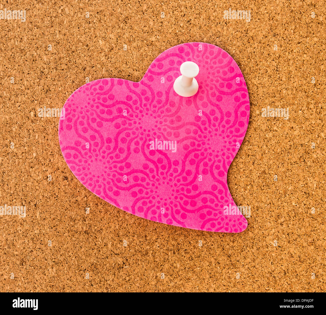 Pink heart memo with pattern pinned to cork board with white push pin ...