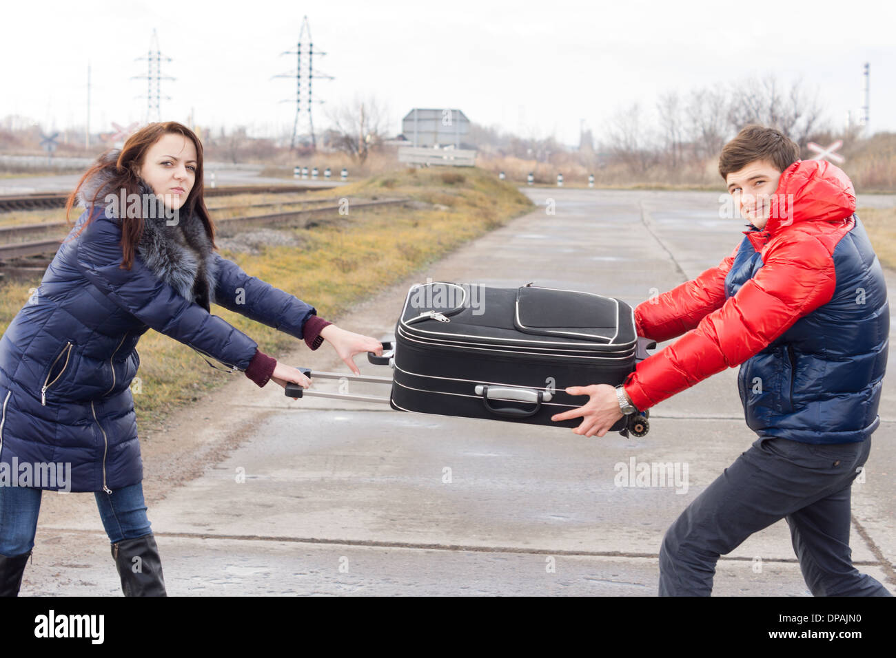 Young man and woman fighting and arguing each pulling on one end of a ...
