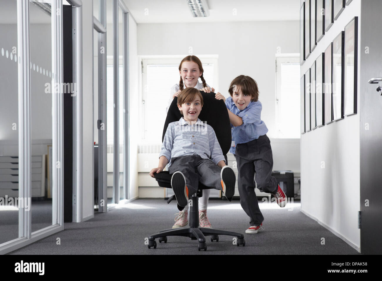 Three children playing in office corridor on office chair Stock Photo ...