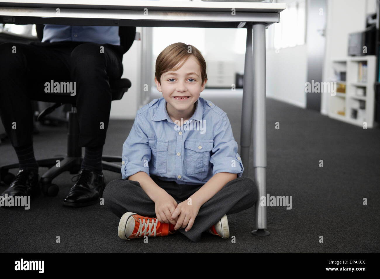 Boy sitting on floor with businessman working at desk Stock Photo - Alamy