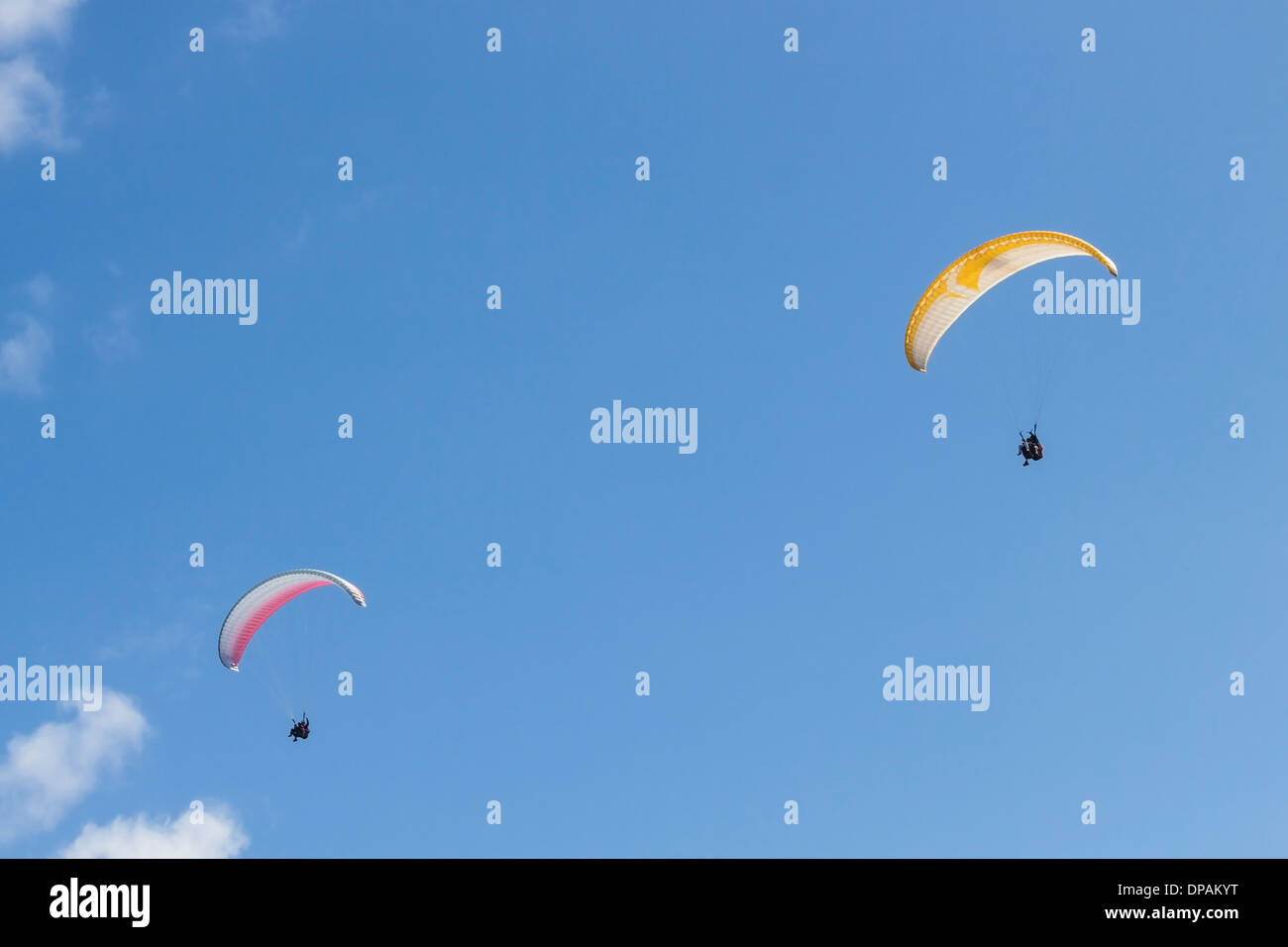 Two tandem paragliders on bright blue sky Stock Photo - Alamy