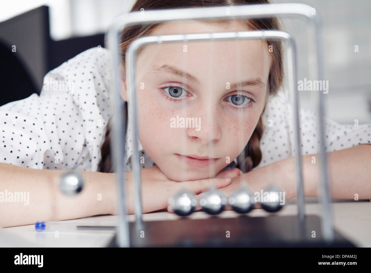 Girl playing with newton's cradle on desk Stock Photo - Alamy