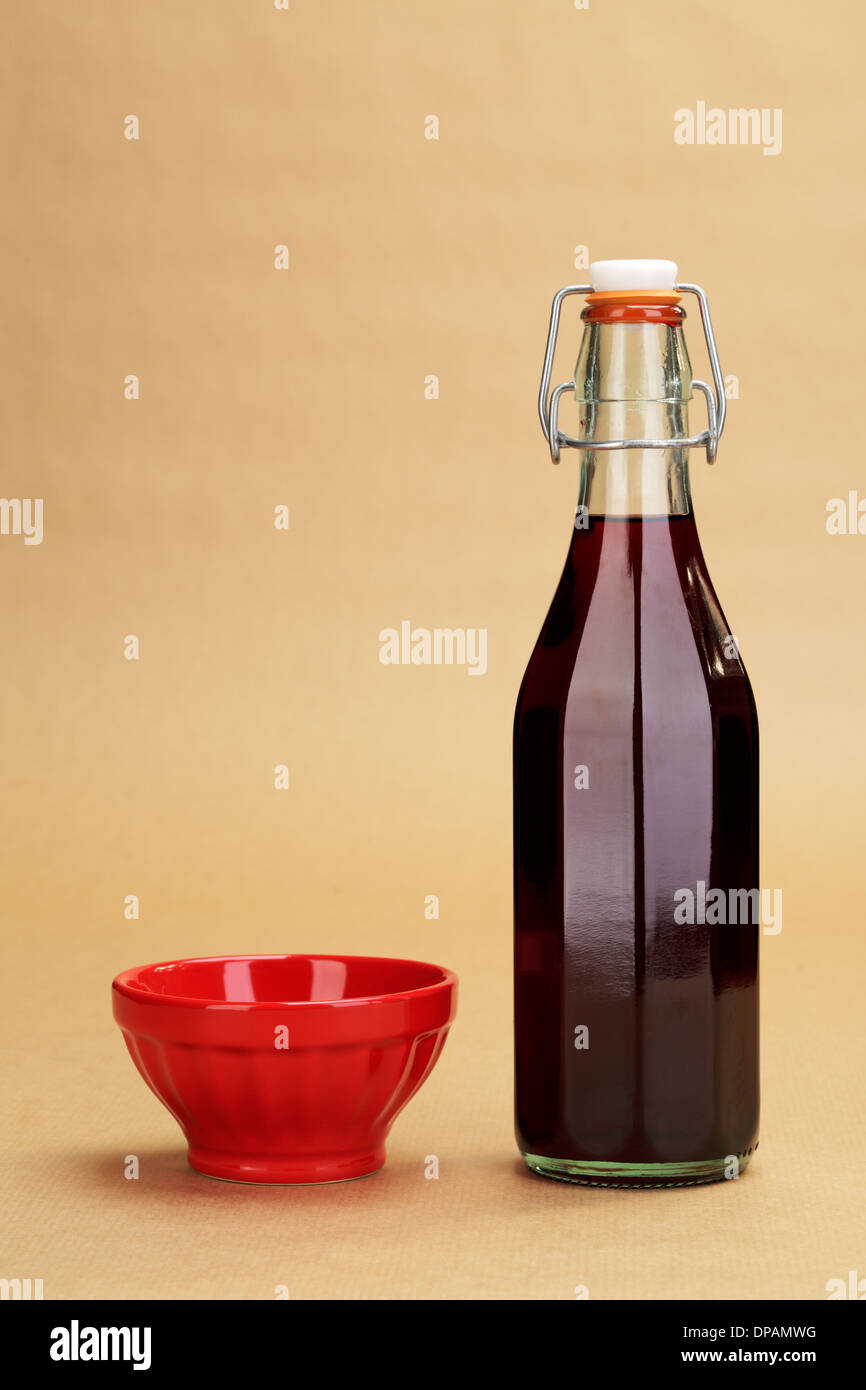 An empty red ceramic bowl and a classic bottle of a home made red wine ...