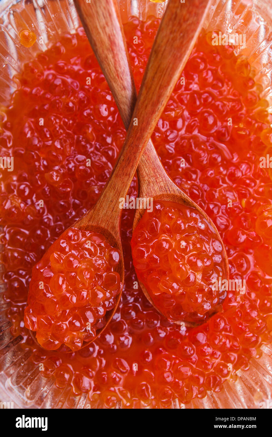 Red caviar on wooden spoons on caviar background Stock Photo - Alamy