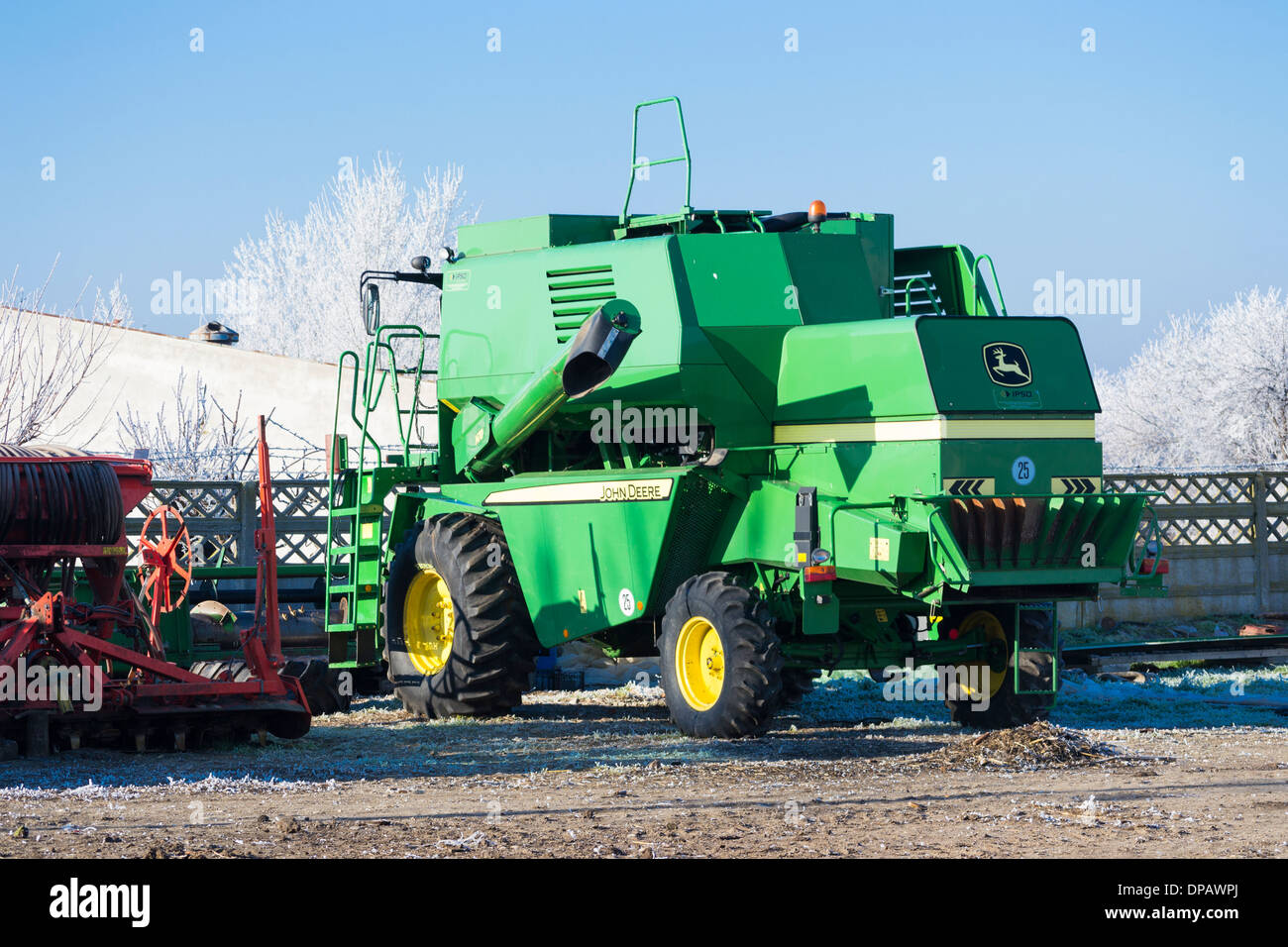 Green John Deere combine harvester parked in a farm yard on a winter ...