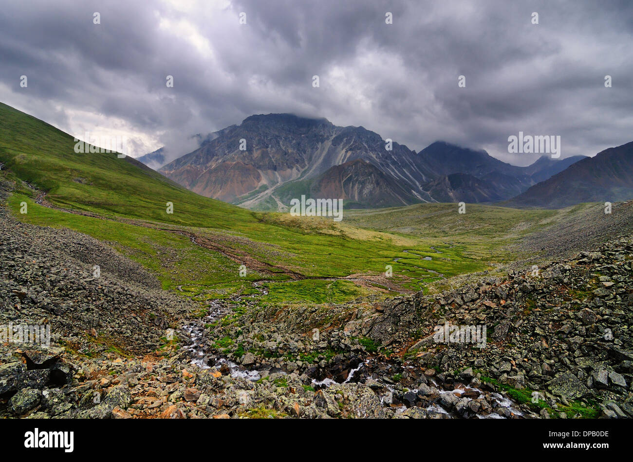 Cloudy sky over the alpine tundra at the origins of the mountain river ...