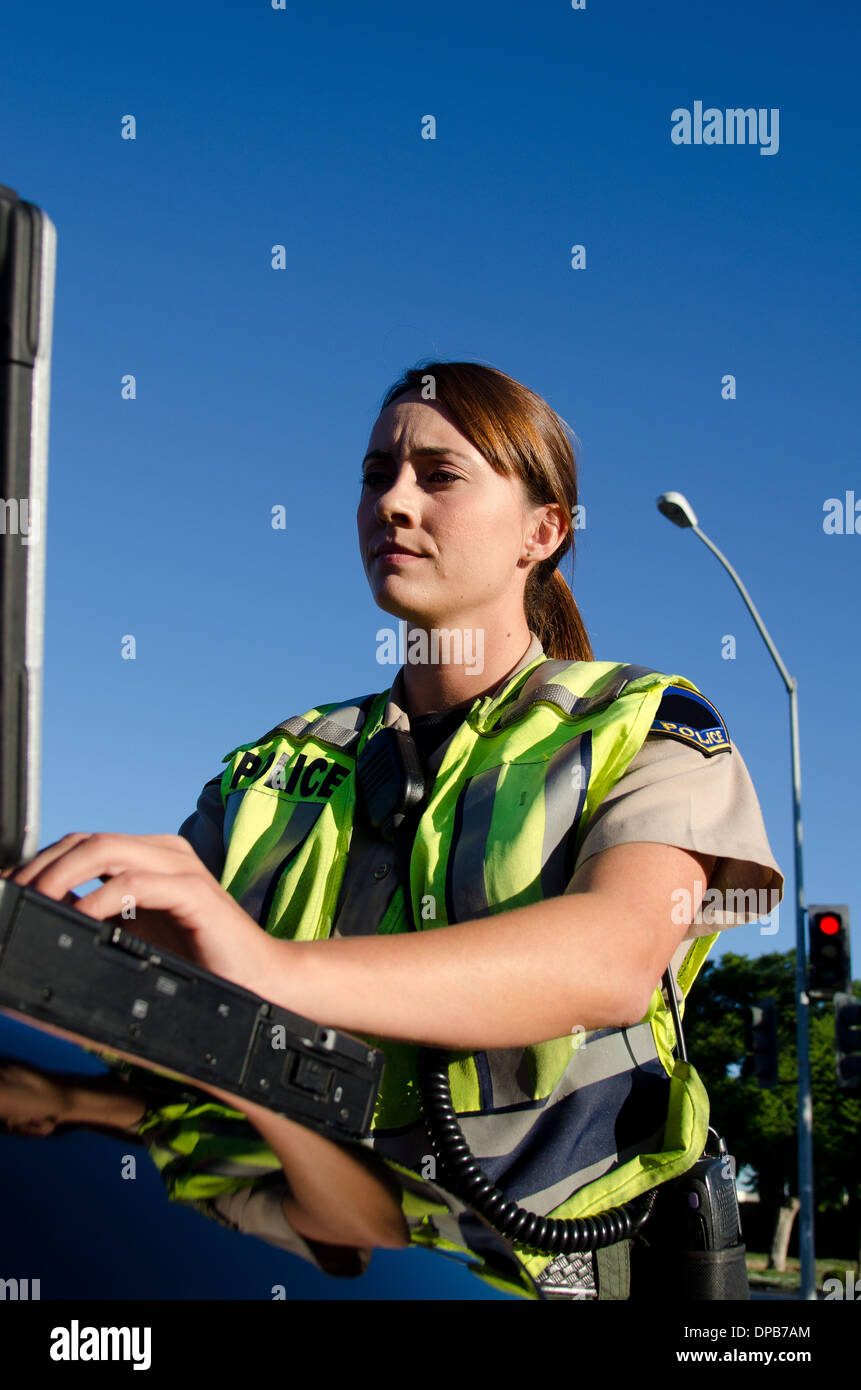 a female police officer types on her lap top computer while on a call ...