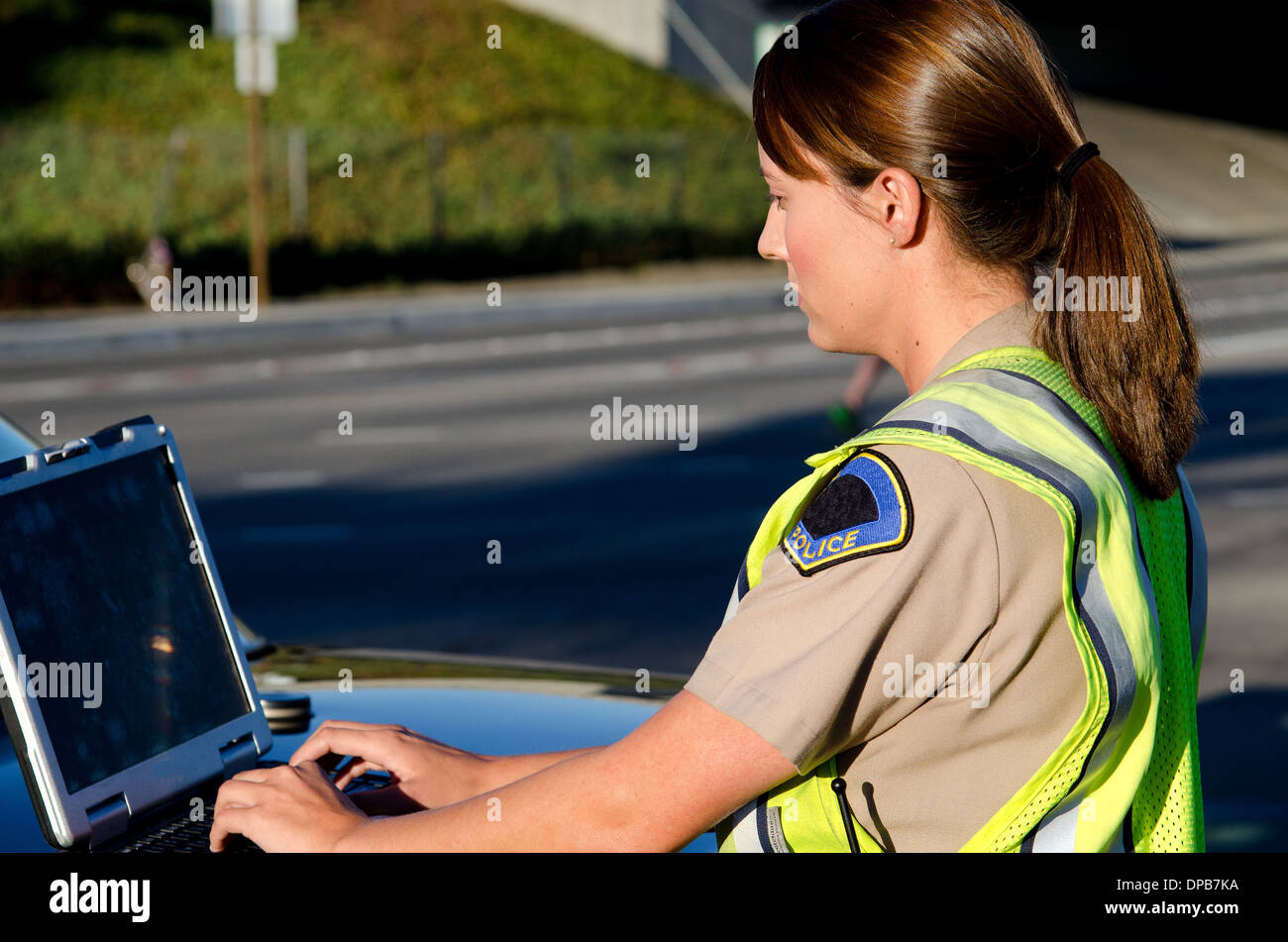 a female police officer types on her lap top computer while on a call ...
