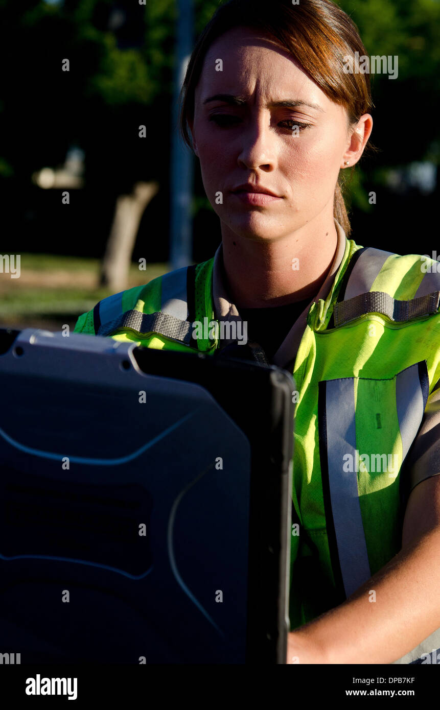 a female police officer types on her lap top computer while on a call ...