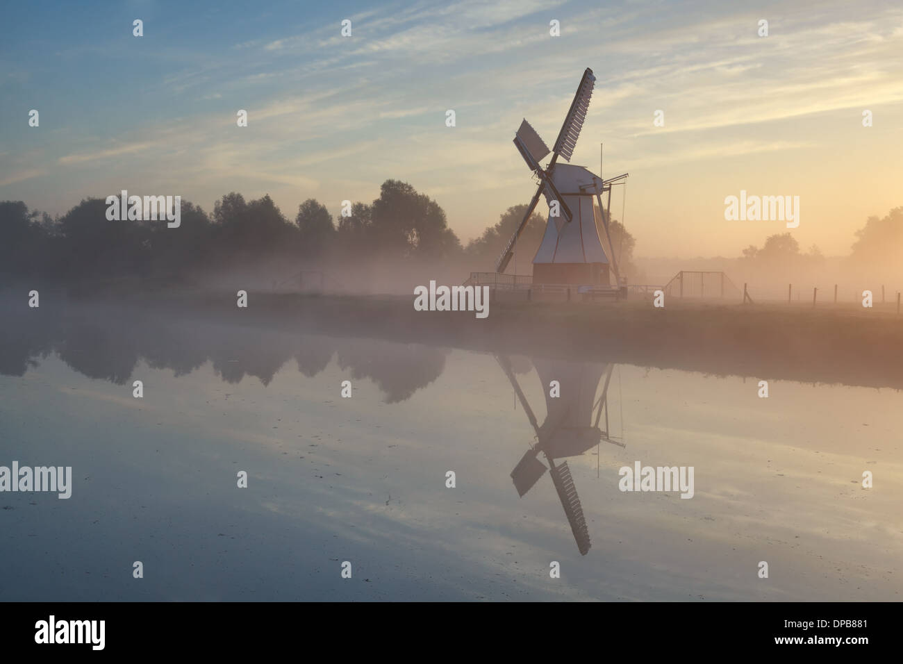 windmill in morning sunshine reflected in river, Holland Stock Photo ...