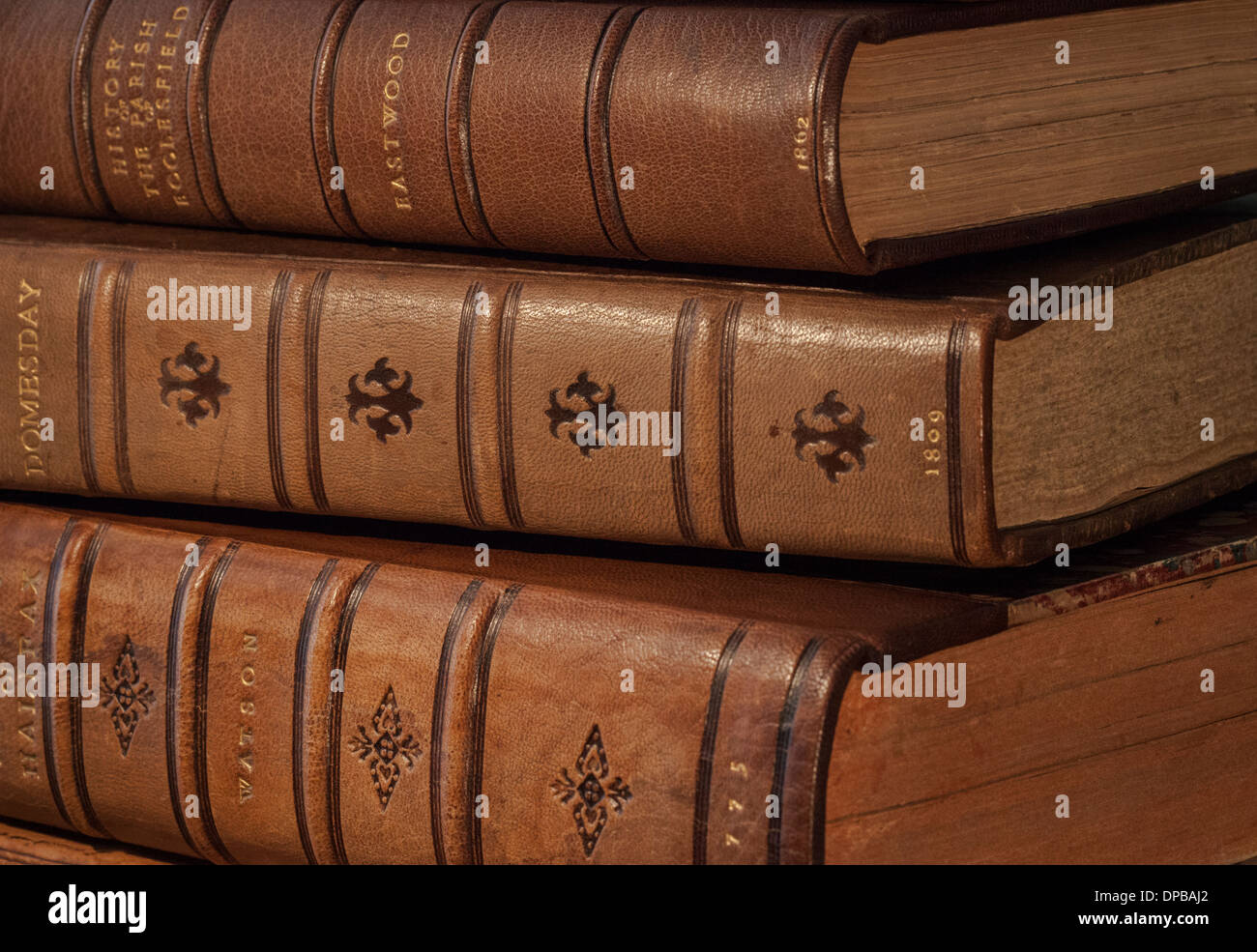 Horizontal stack of three old books in brown leather binding with dates ...