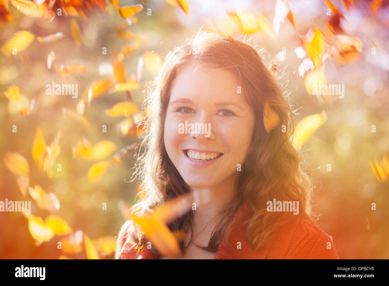 Portrait of happy young woman with swirling autumn leaves around her ...