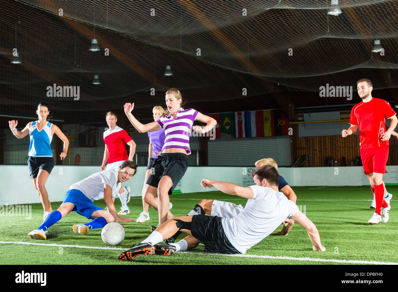 Men and women in mixed sport team playing football or soccer indoor and ...