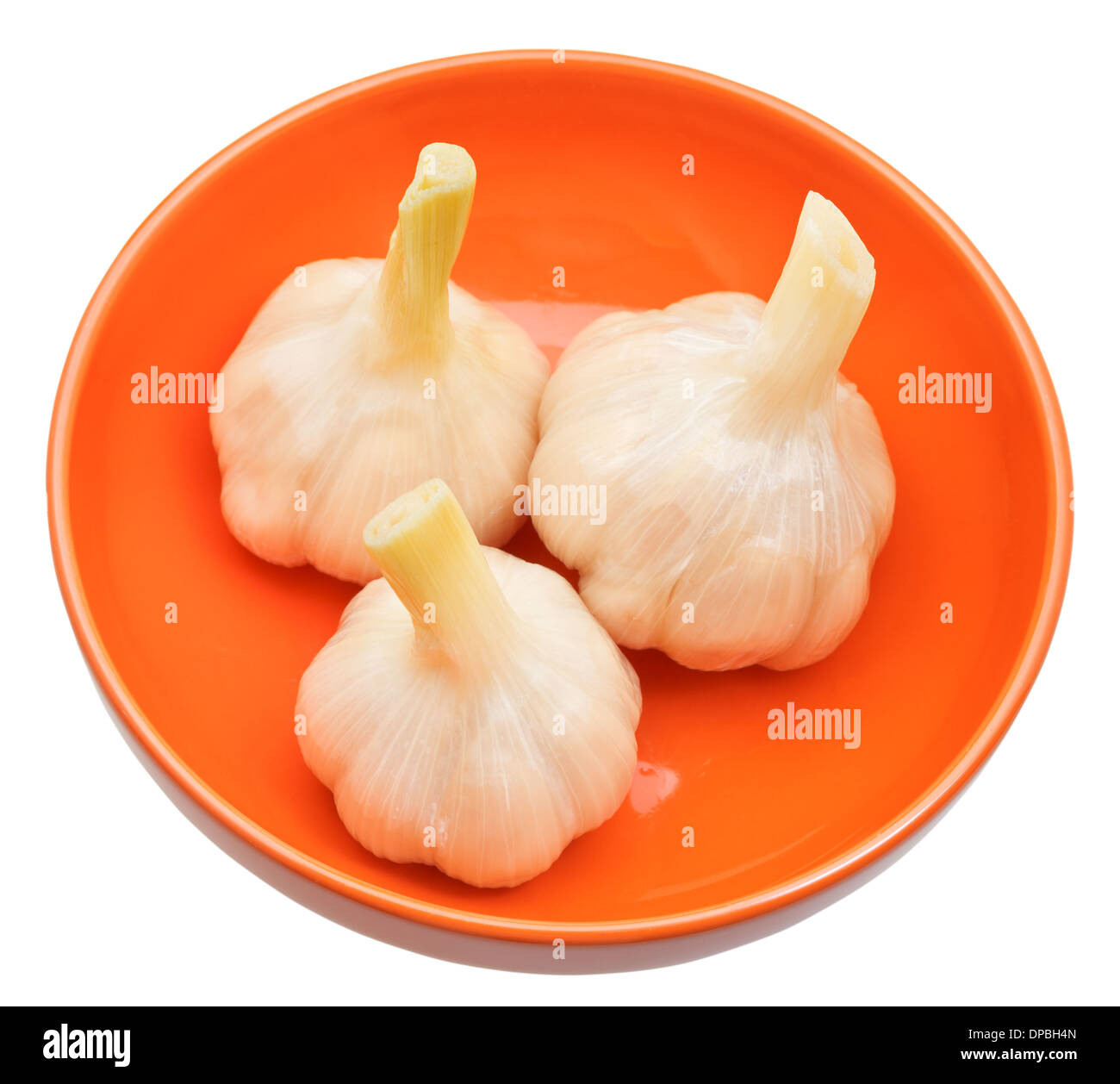 three heads of pickled garlic in ceramic bowl isolated on white ...