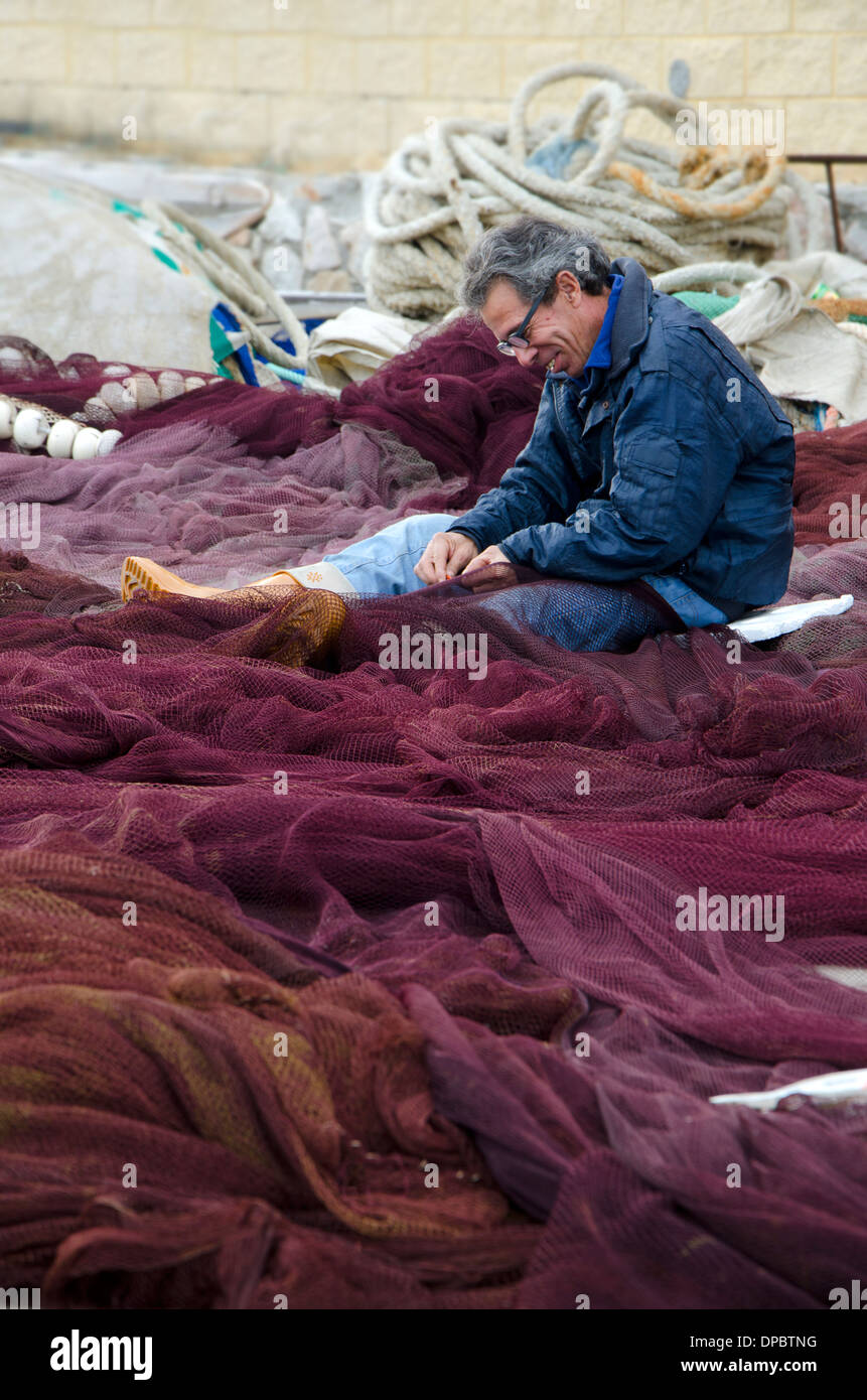Fisherman mending or repairing nylon fishing net with float line in the ...
