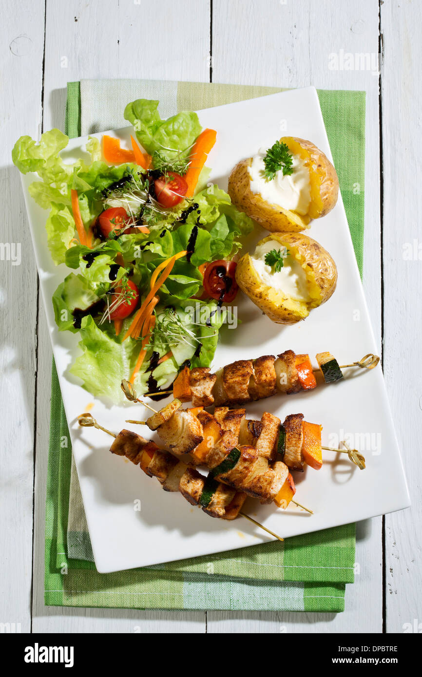 Chicken meat sticks with baked potatoes and mixed salad Stock Photo - Alamy