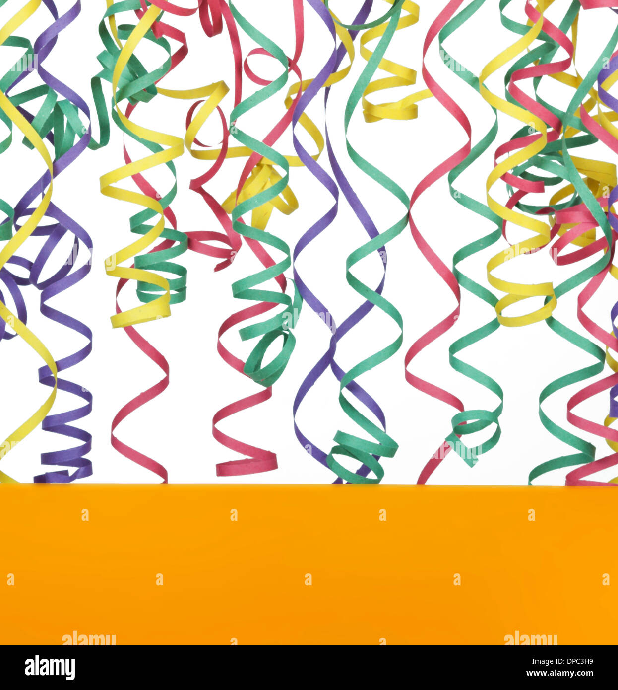 Colorful streamer on white background and orange table Stock Photo - Alamy