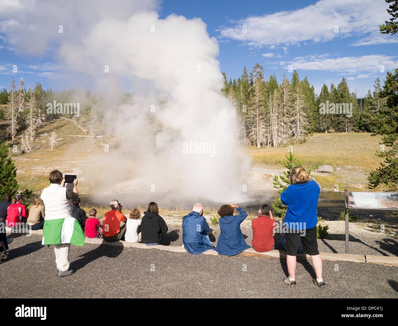 Tourists watching the eruption of Riverside Geyser in Yellowstone ...