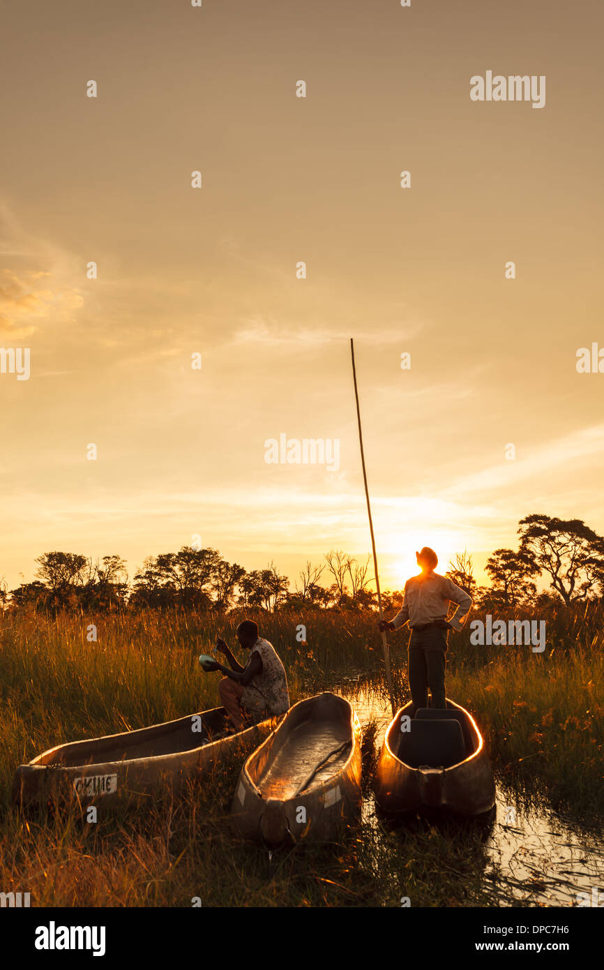 Two guides wait with three makoro canoes for tourists to arrive for ...