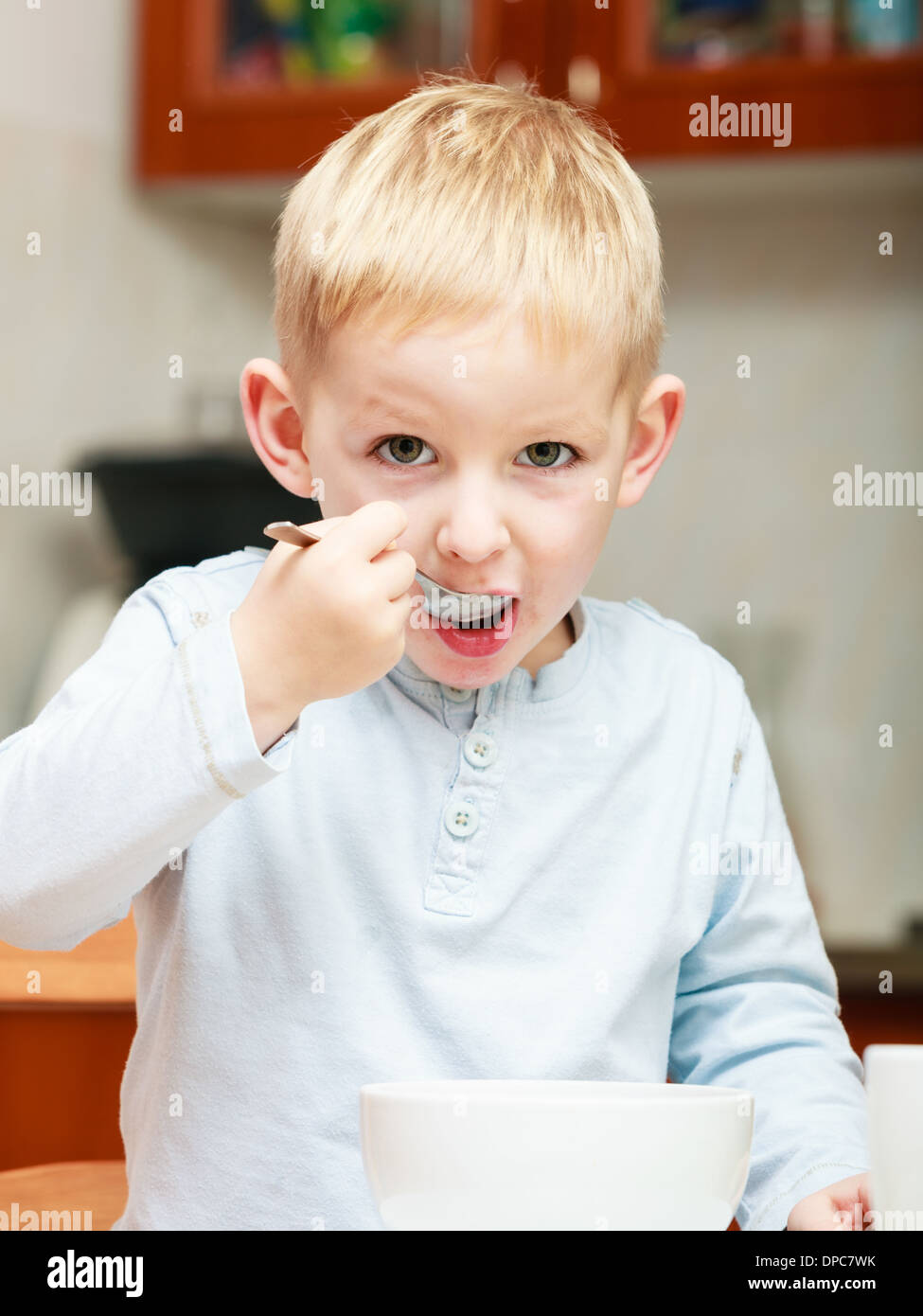 Blond boy kid child eating corn flakes breakfast morning meal at the ...