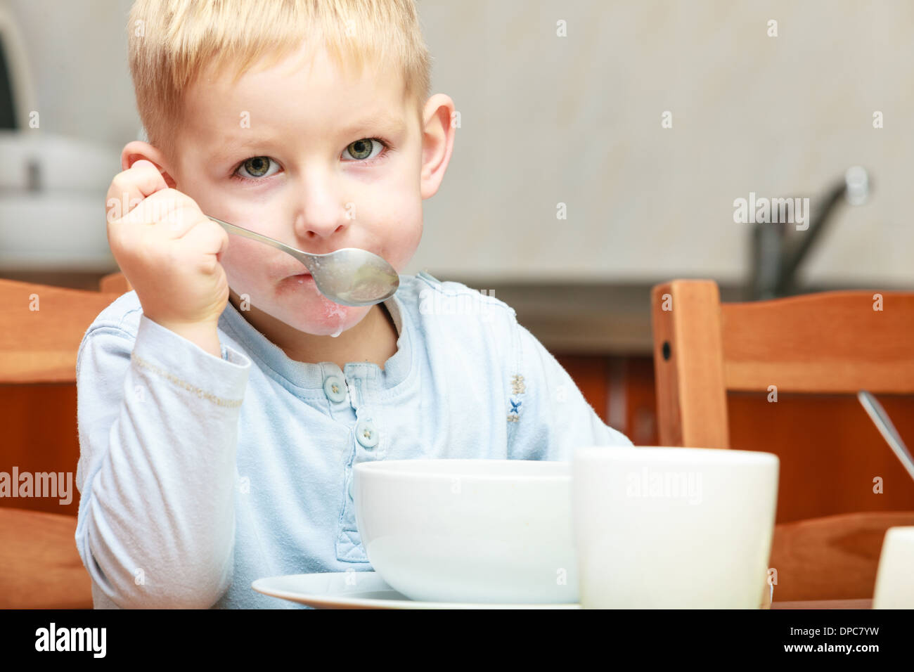 Blond boy kid child eating corn flakes breakfast morning meal at the ...