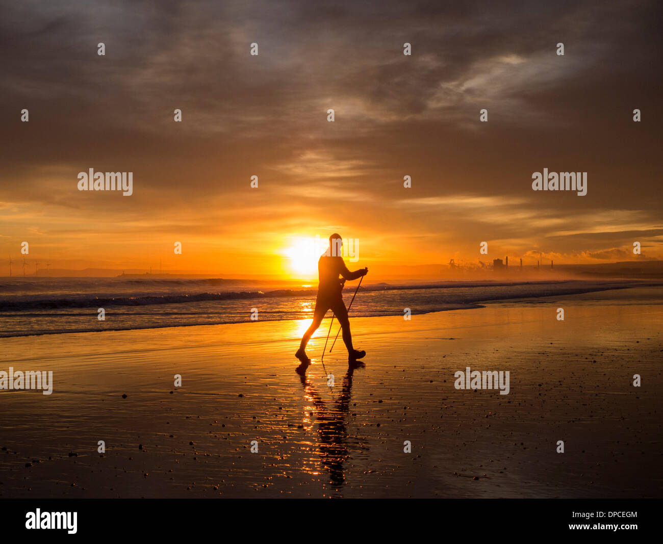 A walker on Seaton Carew beach at sunrise, setting out on the 55km ...