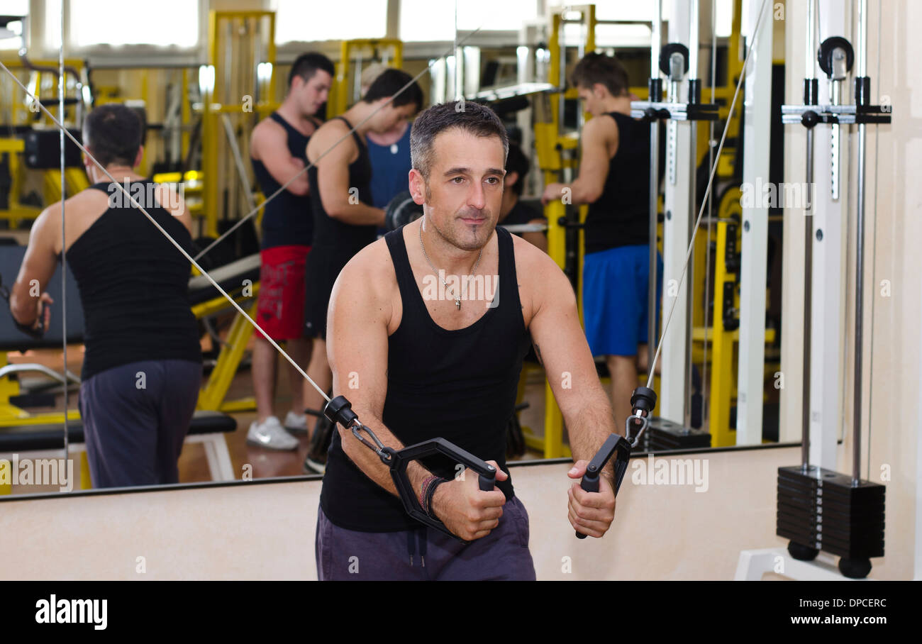 Middle aged man working out with gym equipment, exercising pecs muscles ...