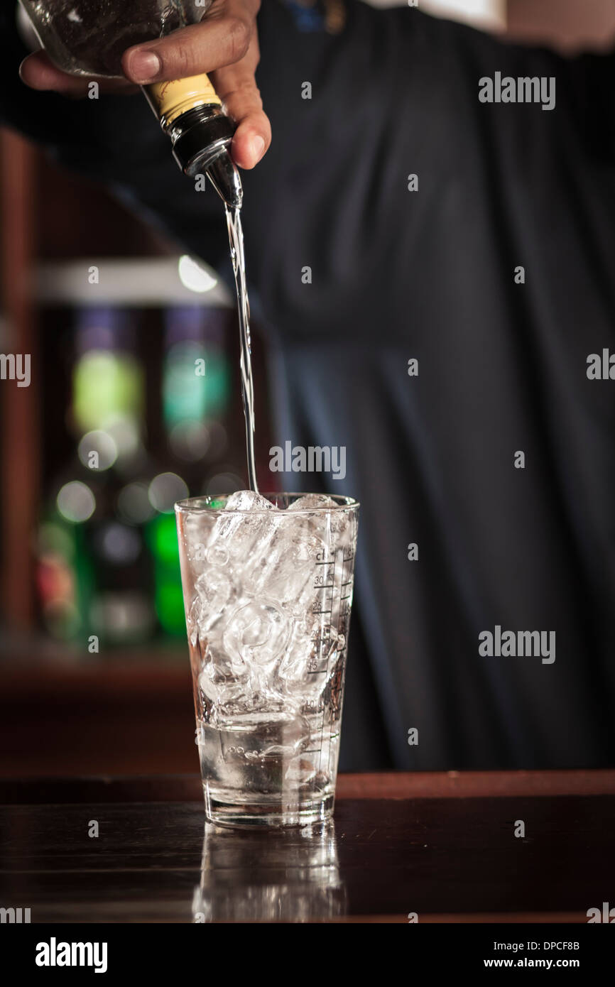 Bartender pouring Gin in a mixing glass with ice cubes, shot on ...