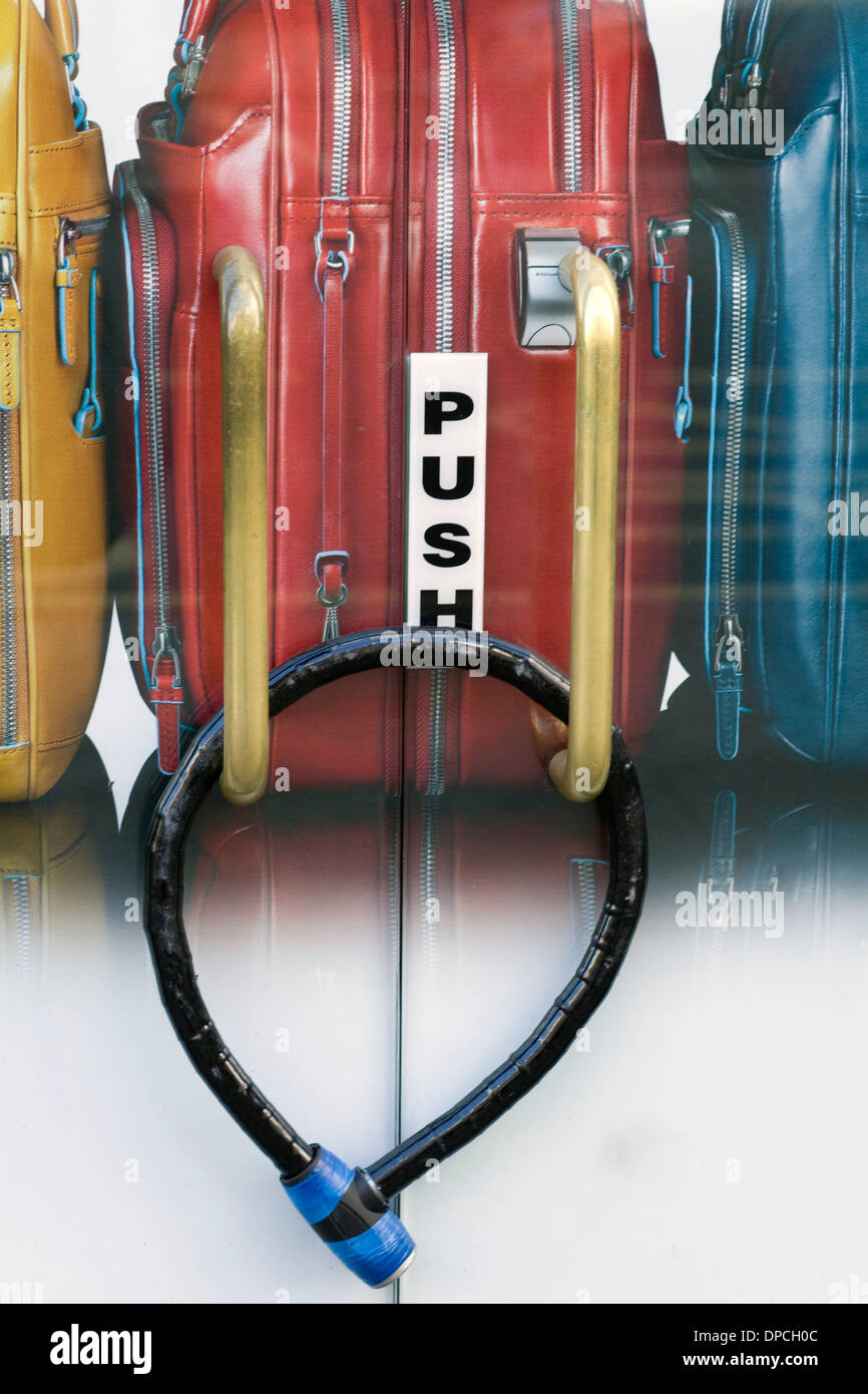 Designer Luggage behind a bike chained locked glass door with Push ...