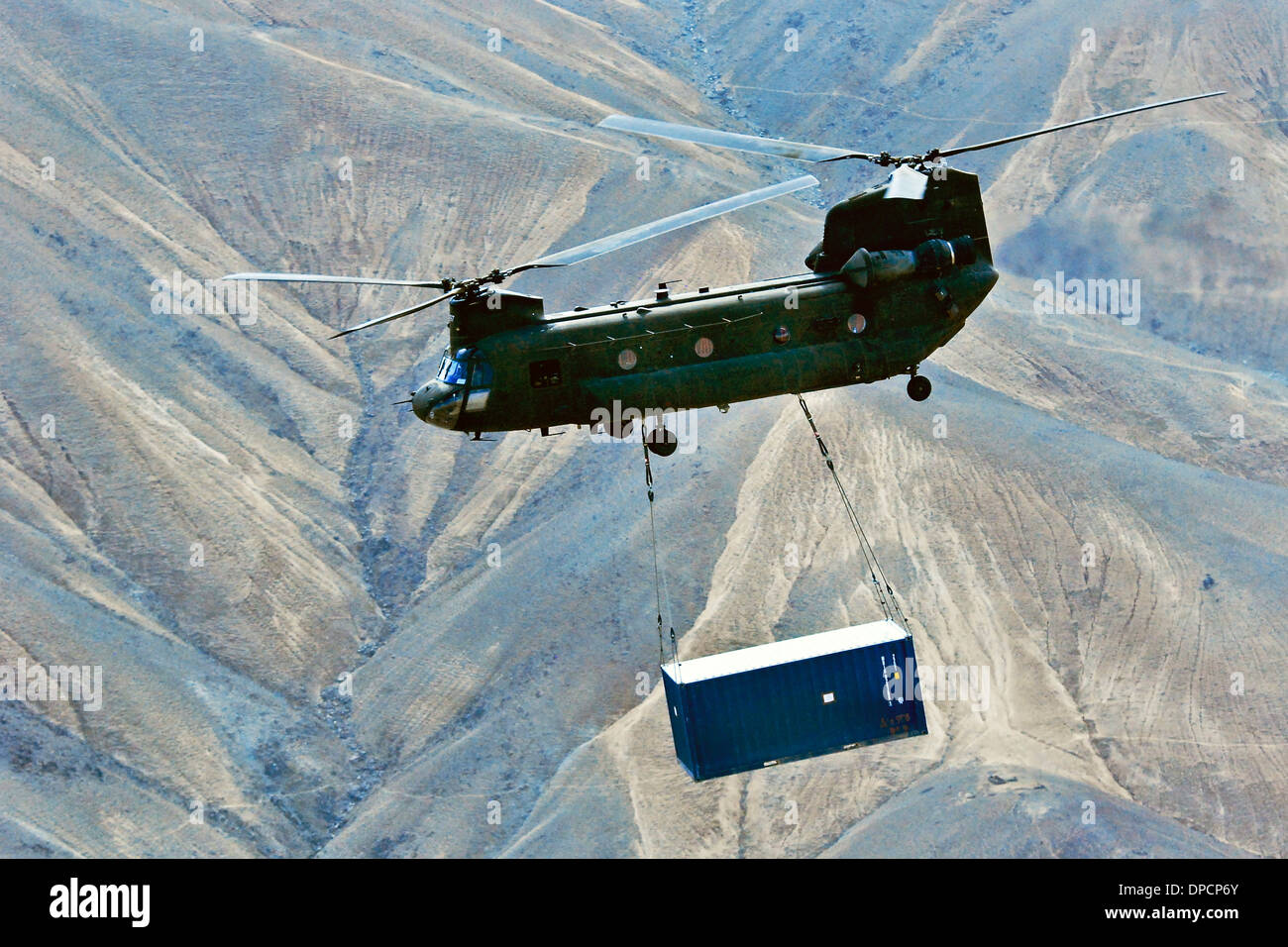 A US Army CH-47 Chinook helicopter carries a sling-loaded shipping ...