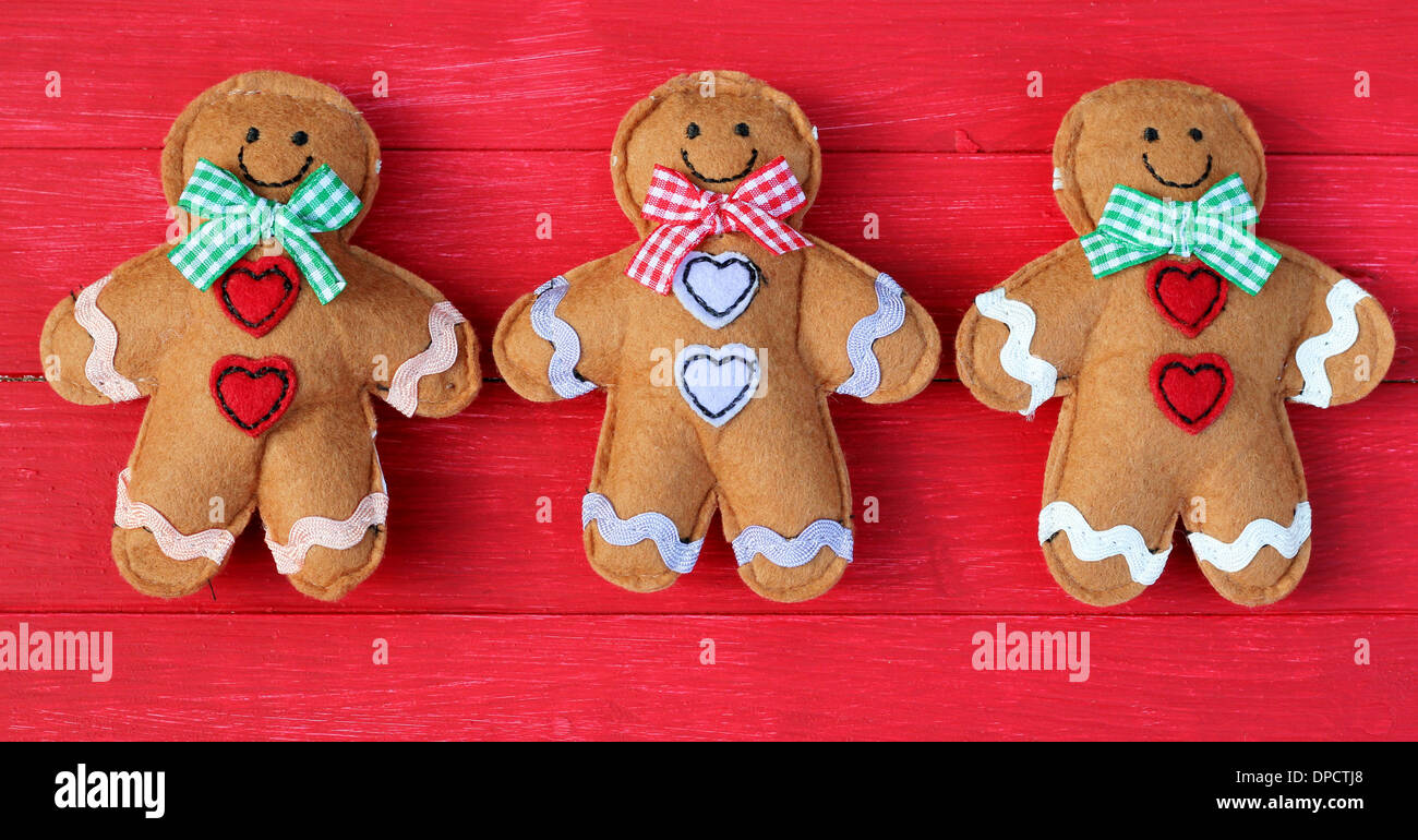 Three felt gingerbread men in a row on red painted board, shabby chic ...