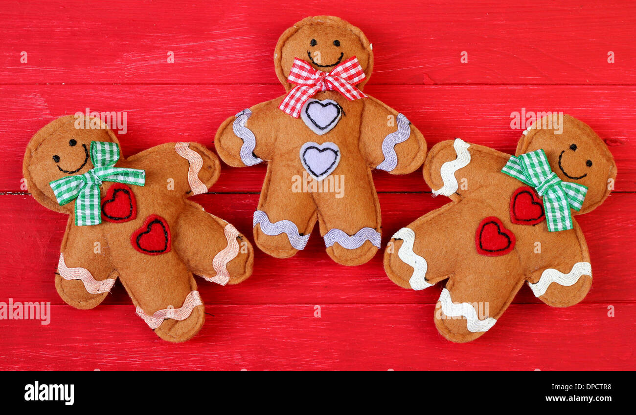 Three felt gingerbread men in a row on red painted board, shabby chic ...