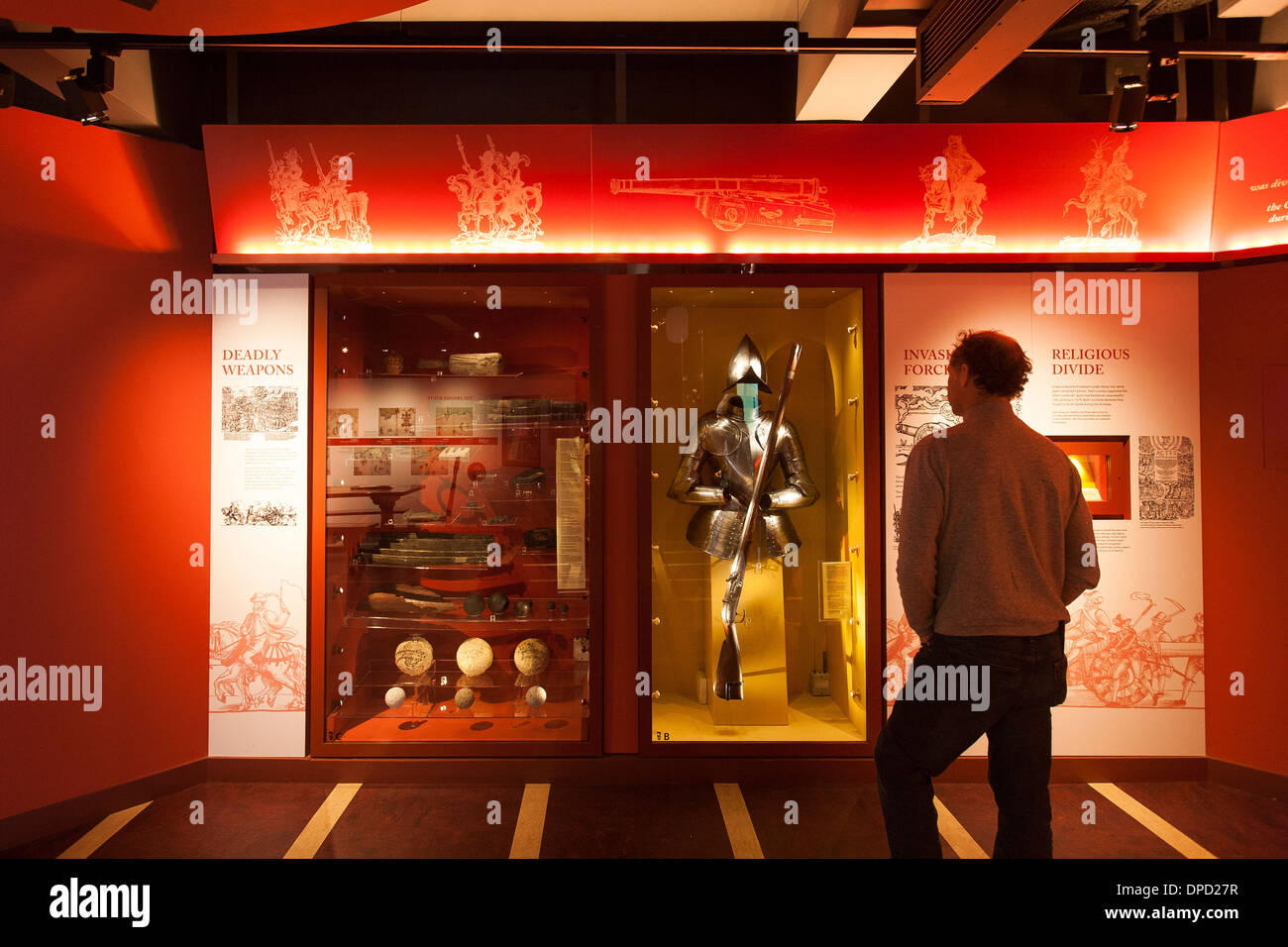 A visitor studies a display of suites of armour and weapons on exhibit ...